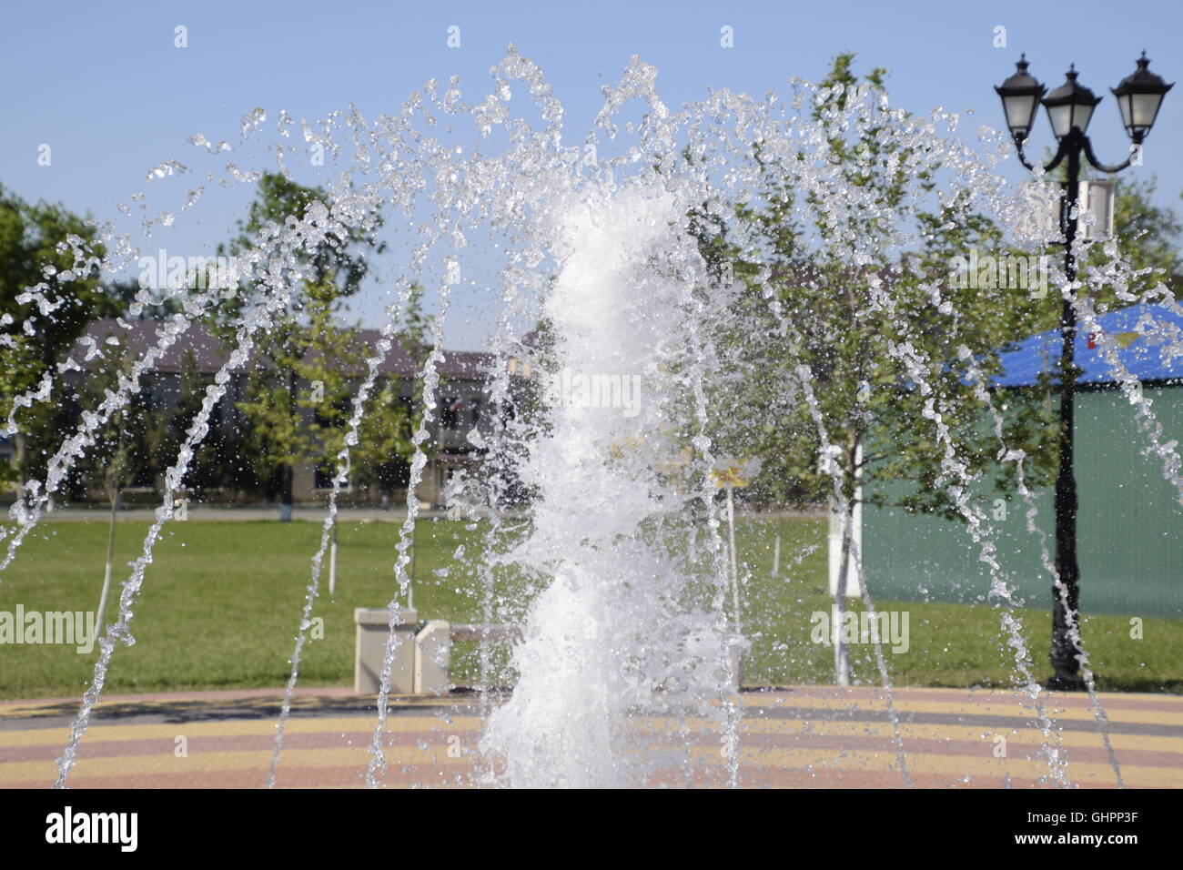 Splashes of a fountain in the park. Beautiful water jet emitted ...