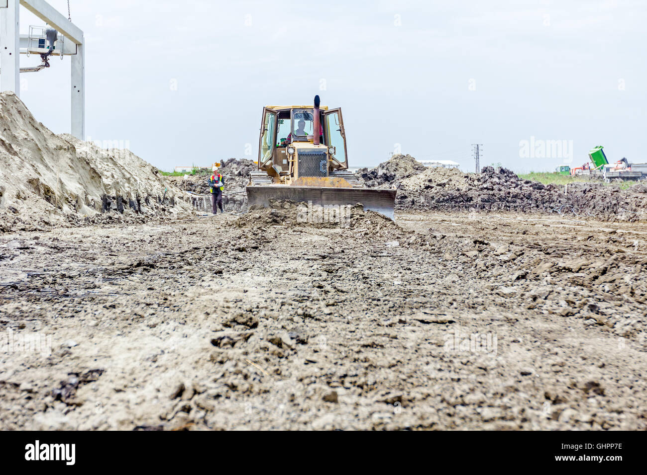 Front view on bulldozer while he moving, leveling ground at building ...