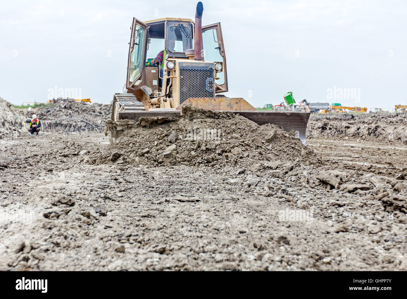 Front view on bulldozer while he moving, leveling ground at building ...