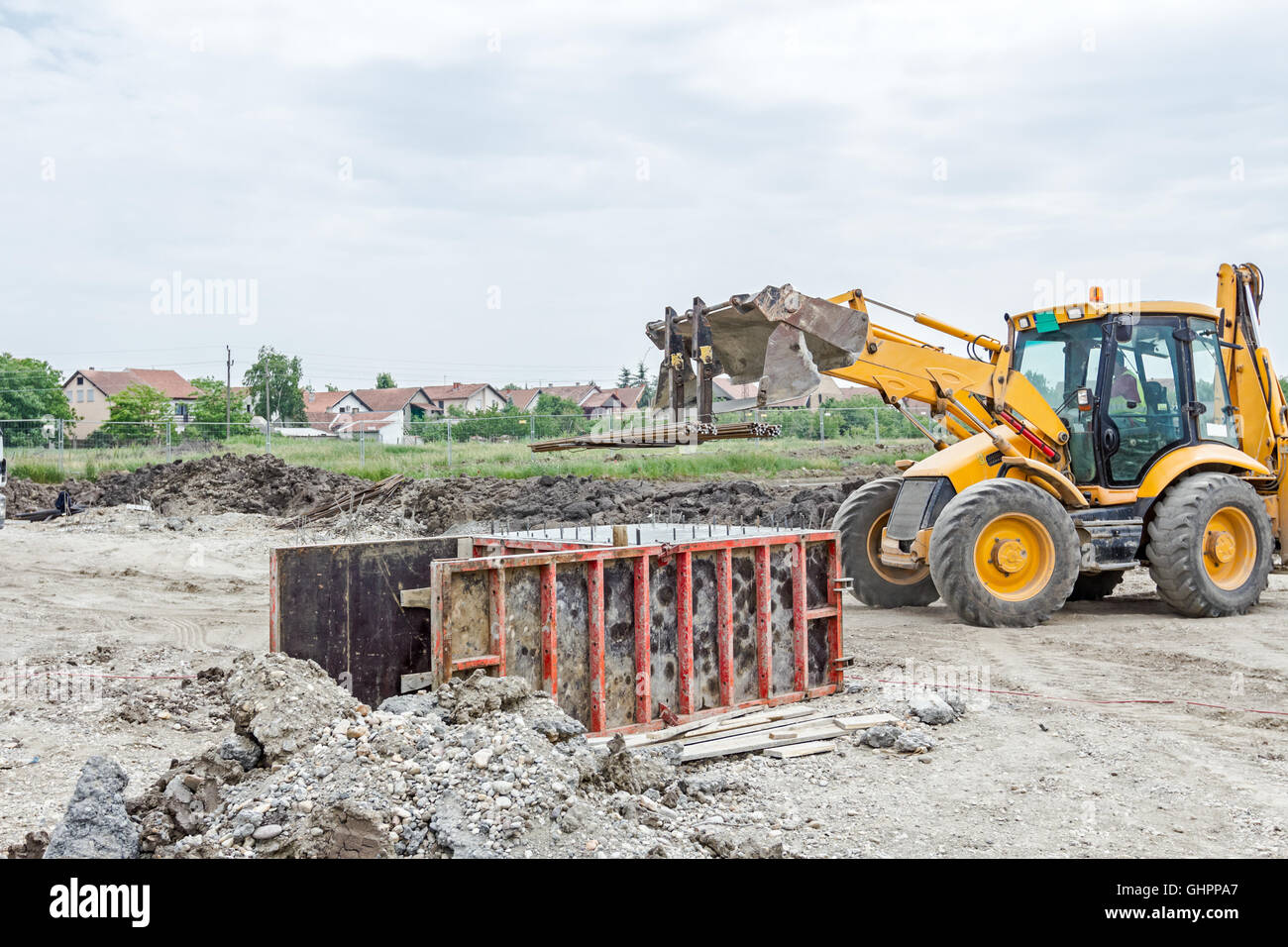 Excavator with inserted forklift is loaded with metal bars for concrete ...