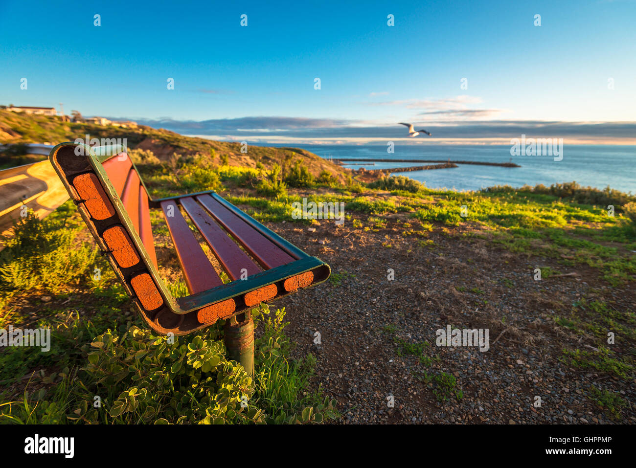 Bench at the edge of the cliff at sunset with clouds above the sea ...