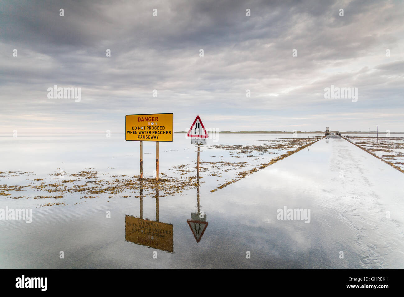 Warning sign reflections on the road to Holy Island as the tide recedes ...