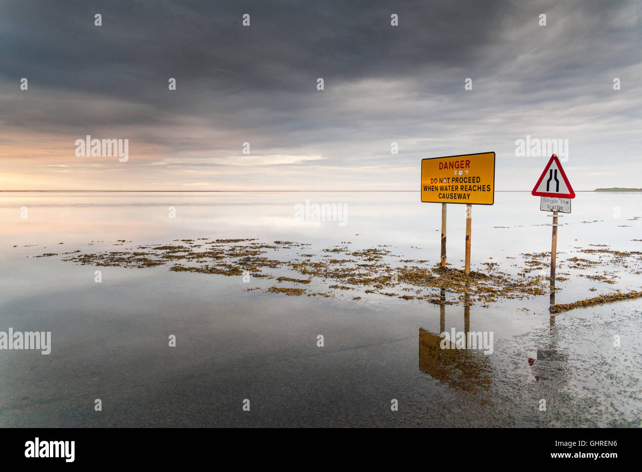 Warning sign reflections on the road to Holy Island as the tide recedes ...