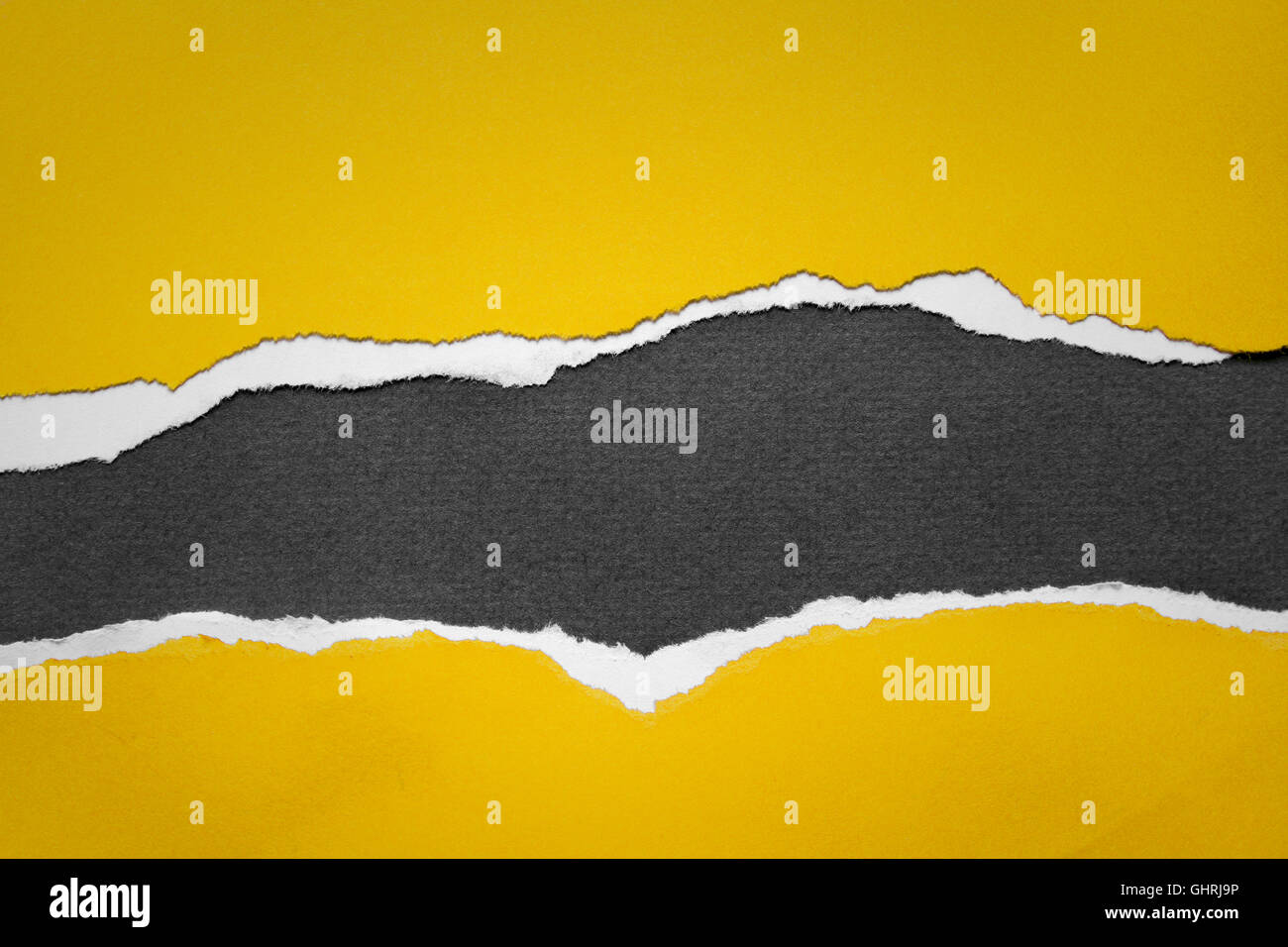 Hole ripped in yellow paper on black background Stock Photo - Alamy