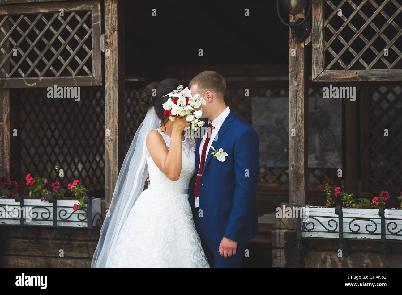 Wedding couple hiding behind the bridal bouquet in a wooden garden ...