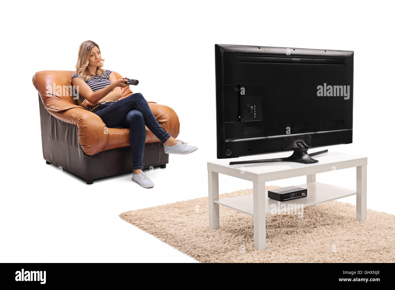 Bored blond woman seated on an armchair watching something dull on ...