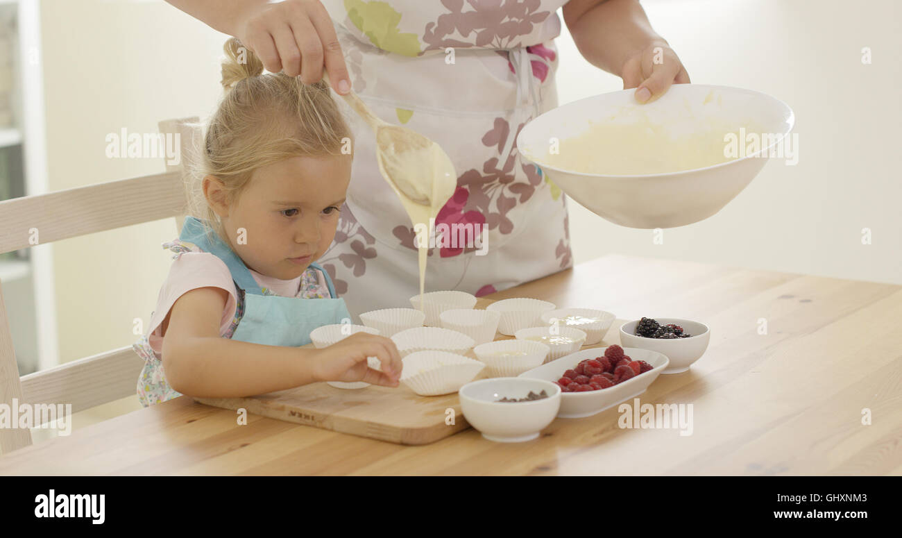 Parent pouring muffin batter into holders Stock Photo - Alamy