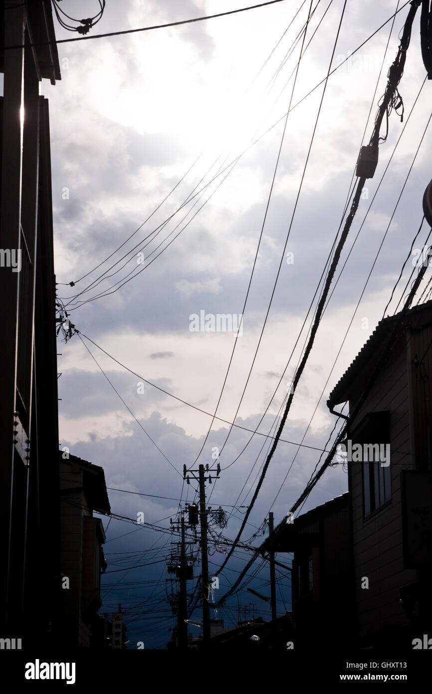 Silhouetted electrical wires running above a street in Kanazawa, Japan ...