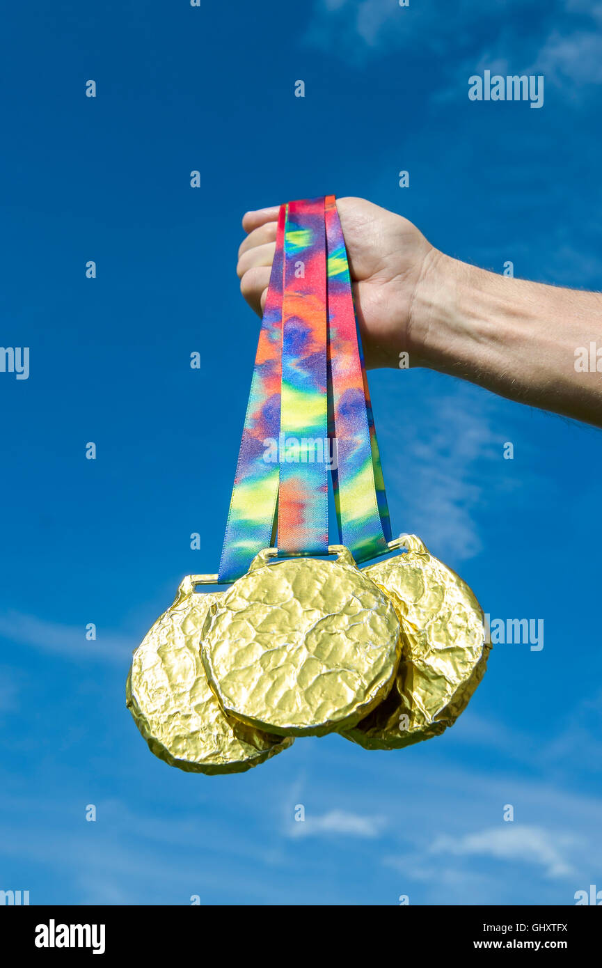 Hand of athlete holding gold medals hanging from colorful ribbons ...