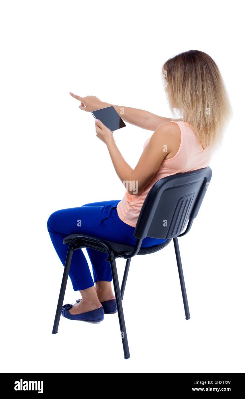 back view of pointing woman sitting on chair and looks at the sc Stock ...