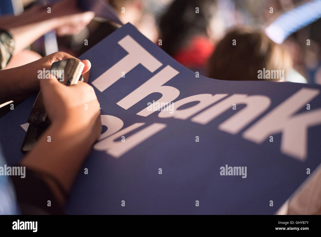 Woman holding "Thank you" sign and camera ahead of President Obama's ...