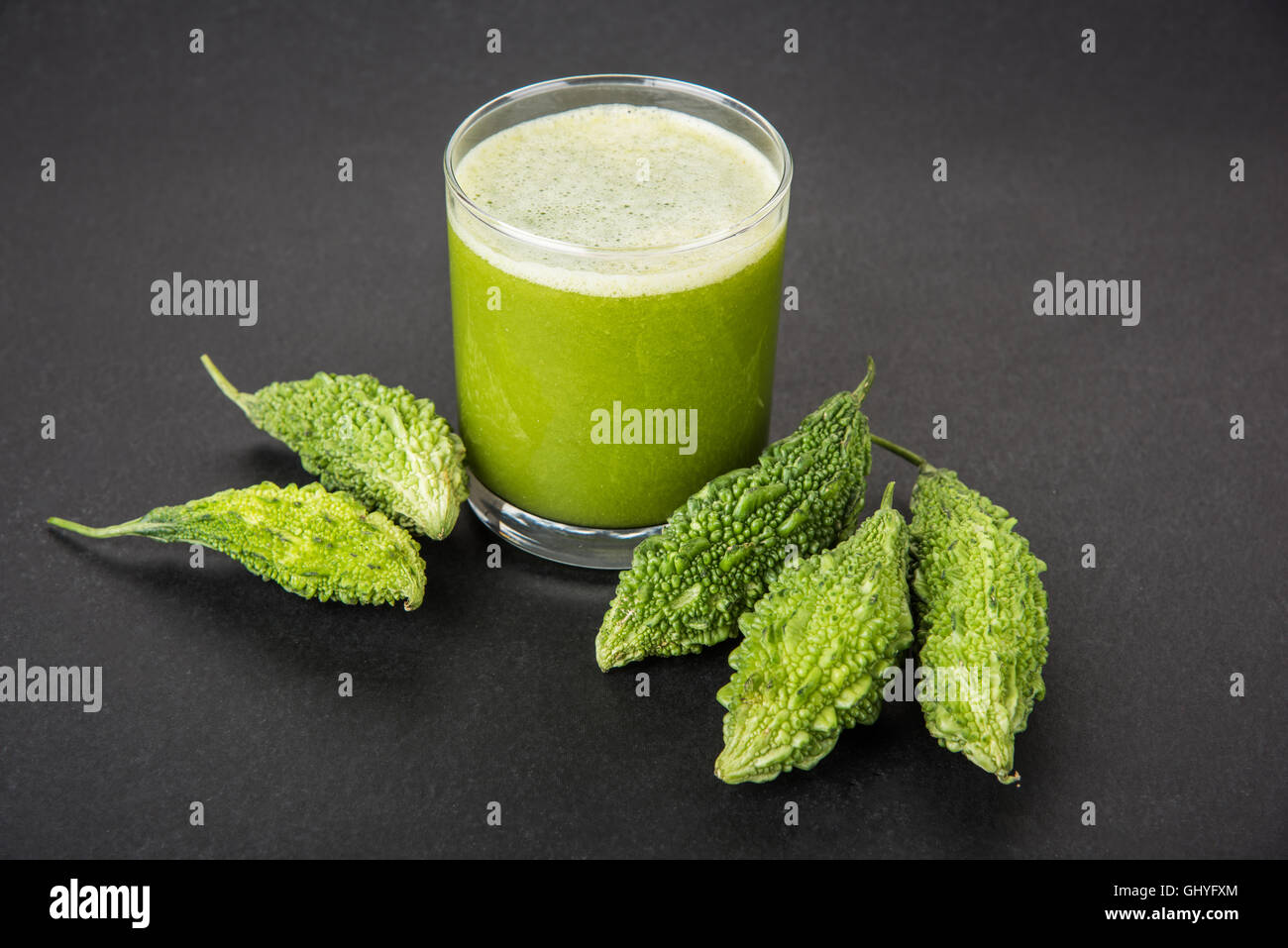 Herbal juice of green momodica in a glass with sliced vegetables ...