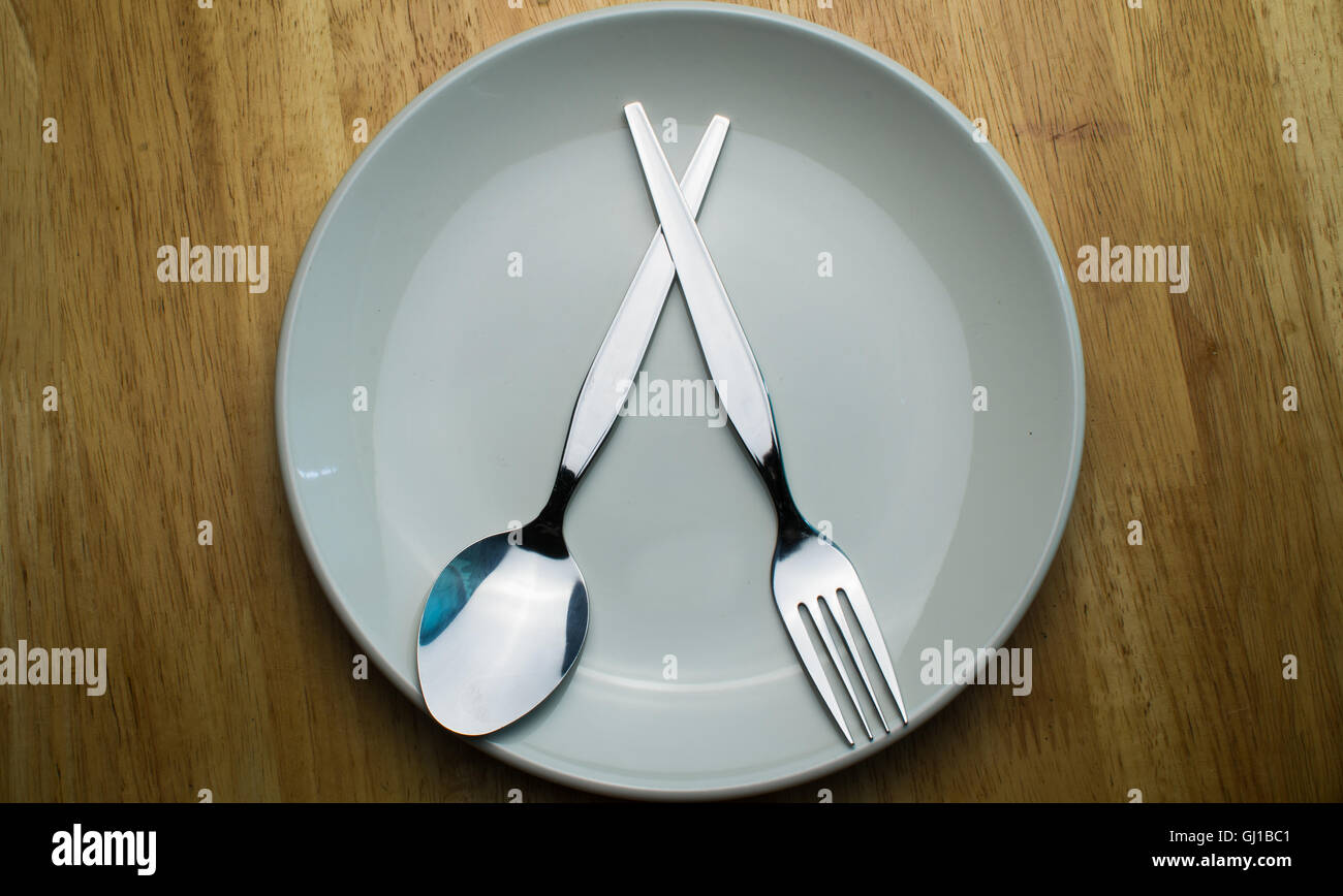 Spoon and fork were placed in a green ceramic plate. Flat lay photo ...