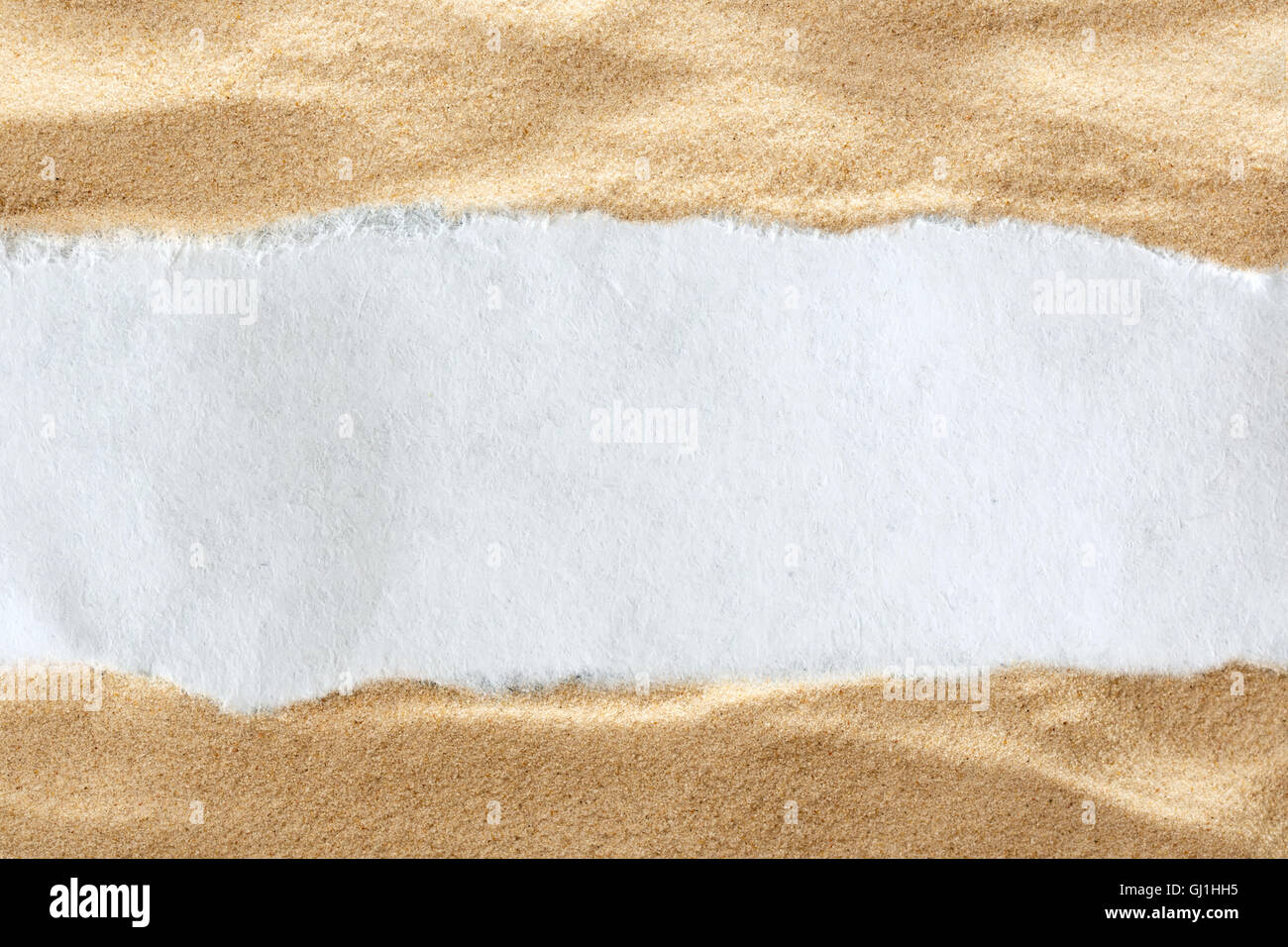Ragged piece of paper on sand background Stock Photo - Alamy