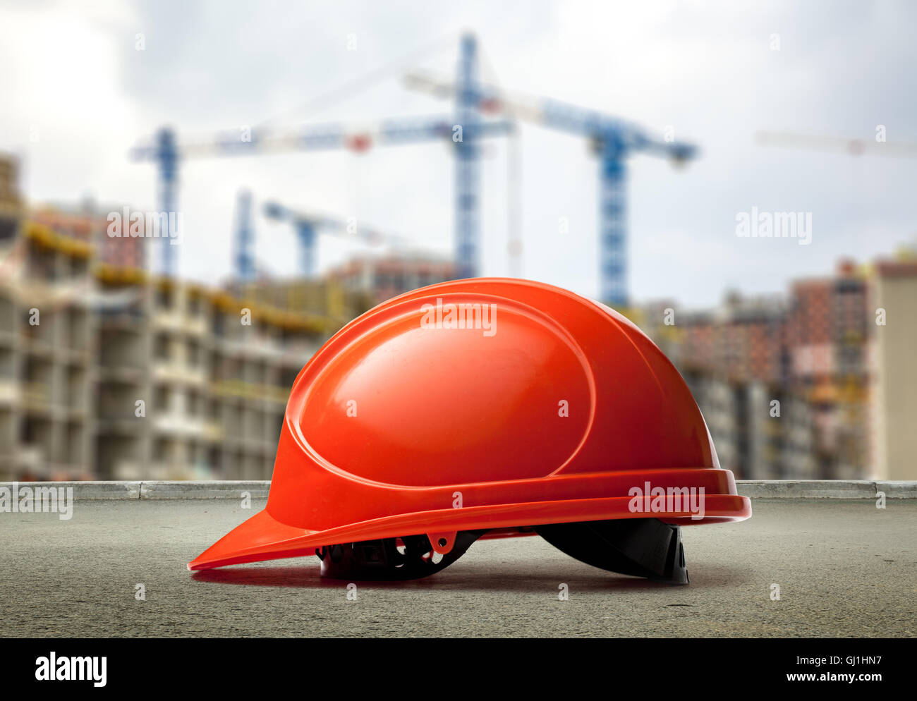 Red helmet on buildings and cranes background Stock Photo - Alamy