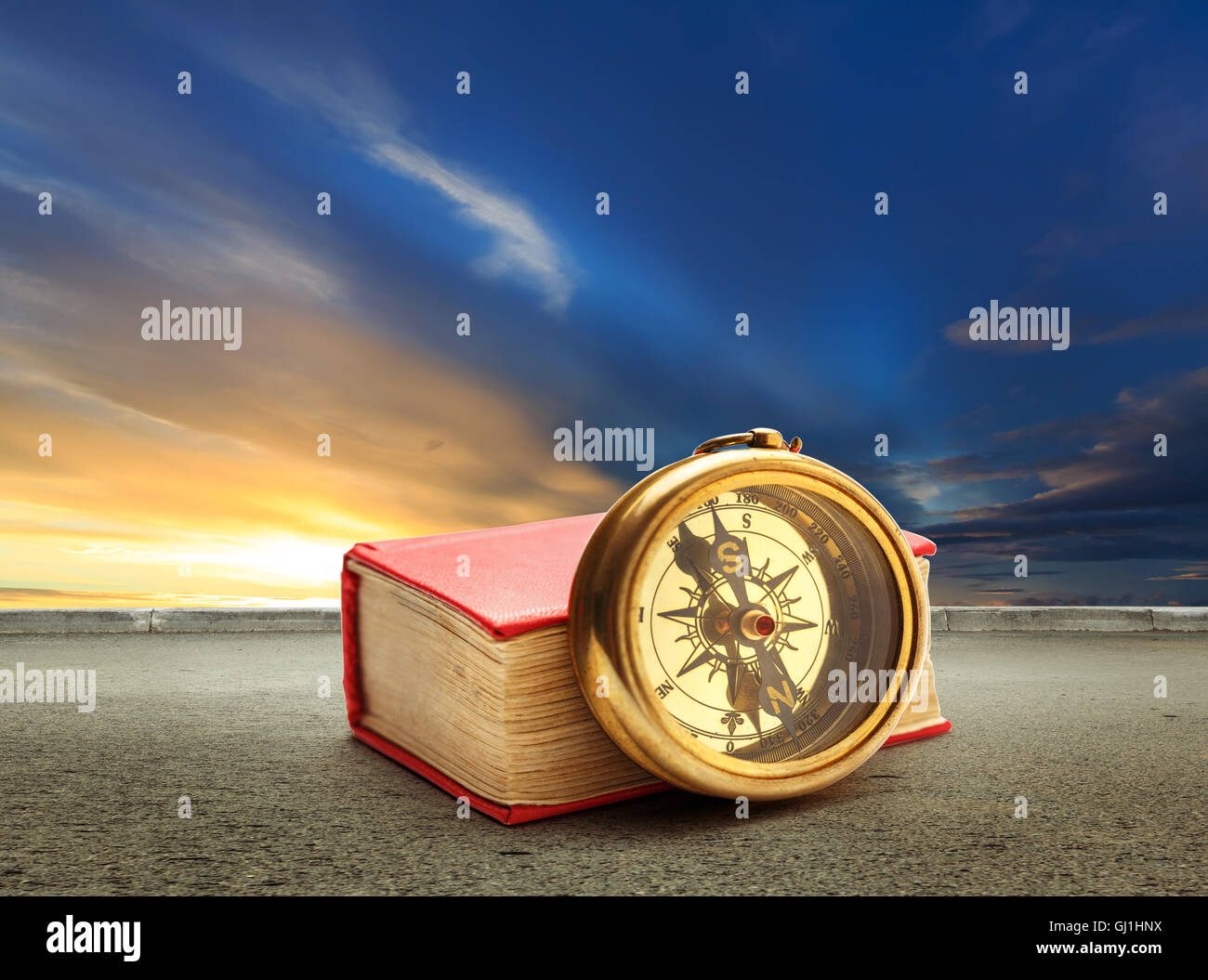 Book and compass at sunset sky with road background Stock Photo - Alamy