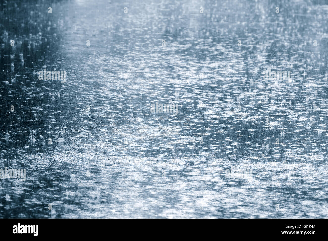 Rain drops rippling in a puddle Stock Photo - Alamy