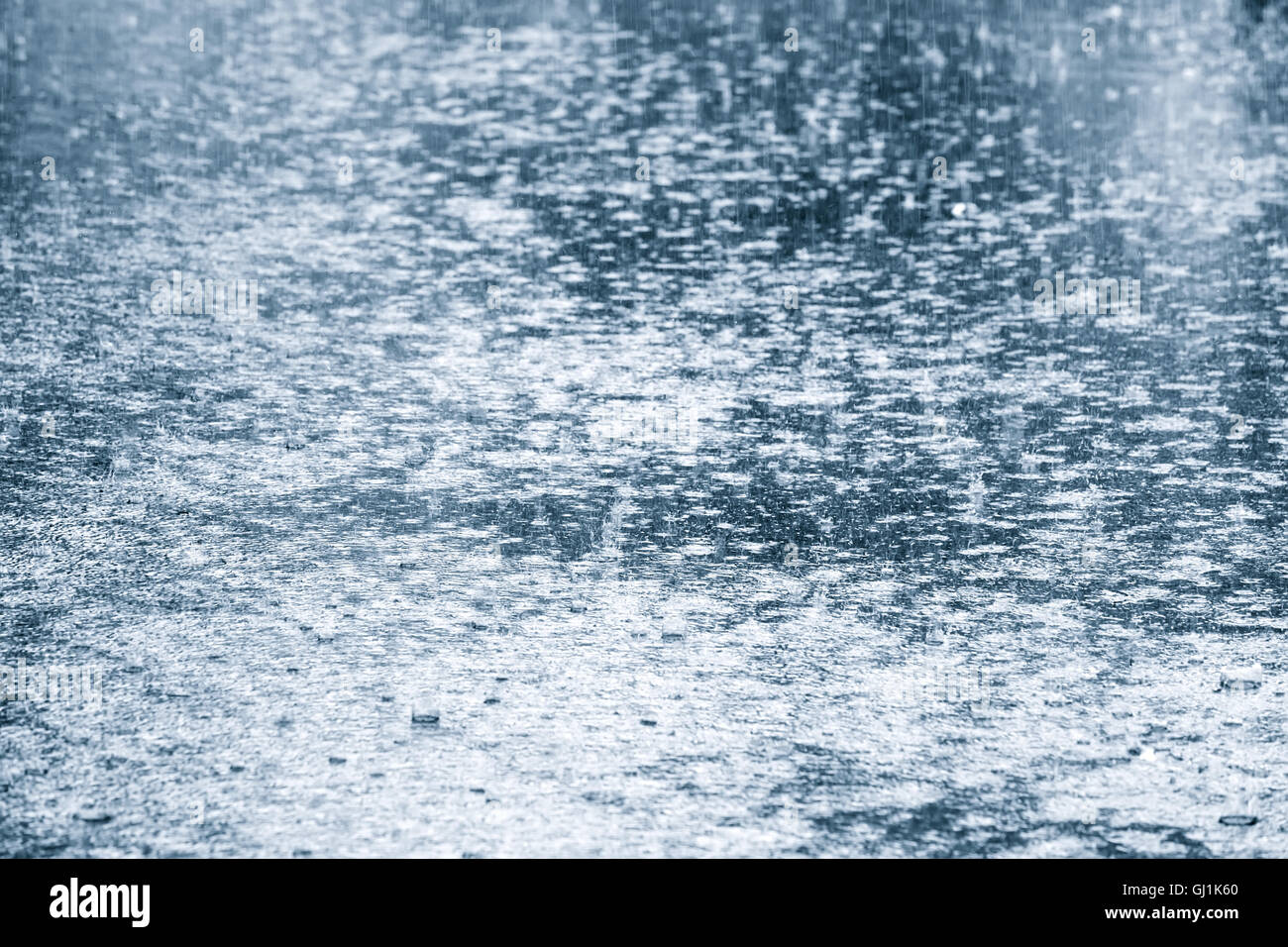 Rain drops rippling in a puddle Stock Photo - Alamy