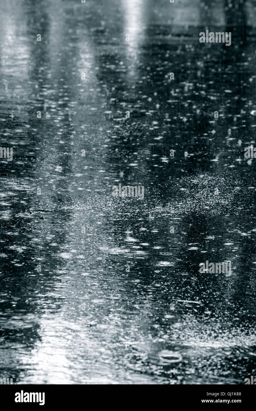 Rain drops rippling in a puddle Stock Photo - Alamy