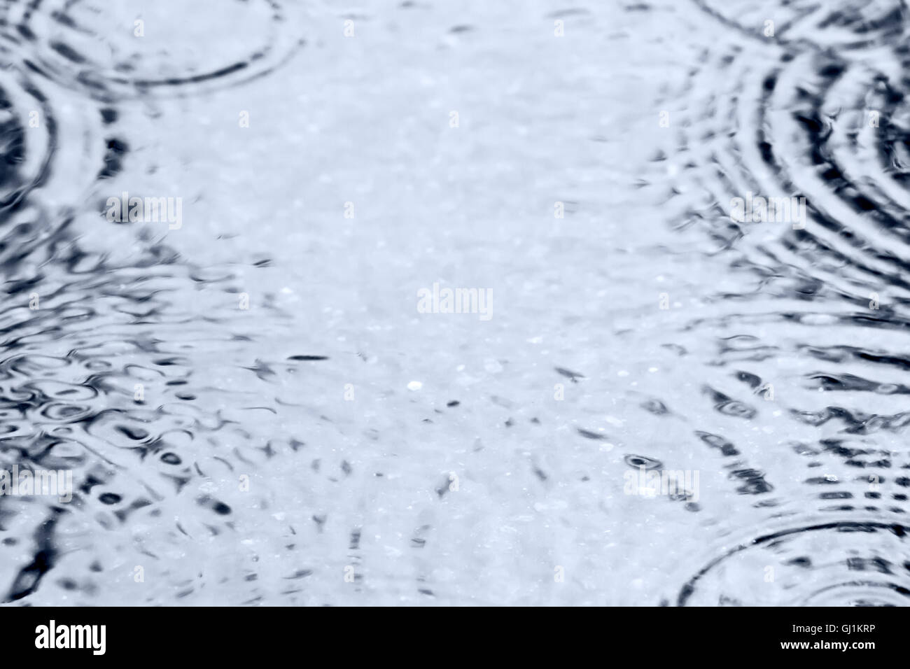 Rain puddle with raindrops rippling Stock Photo - Alamy