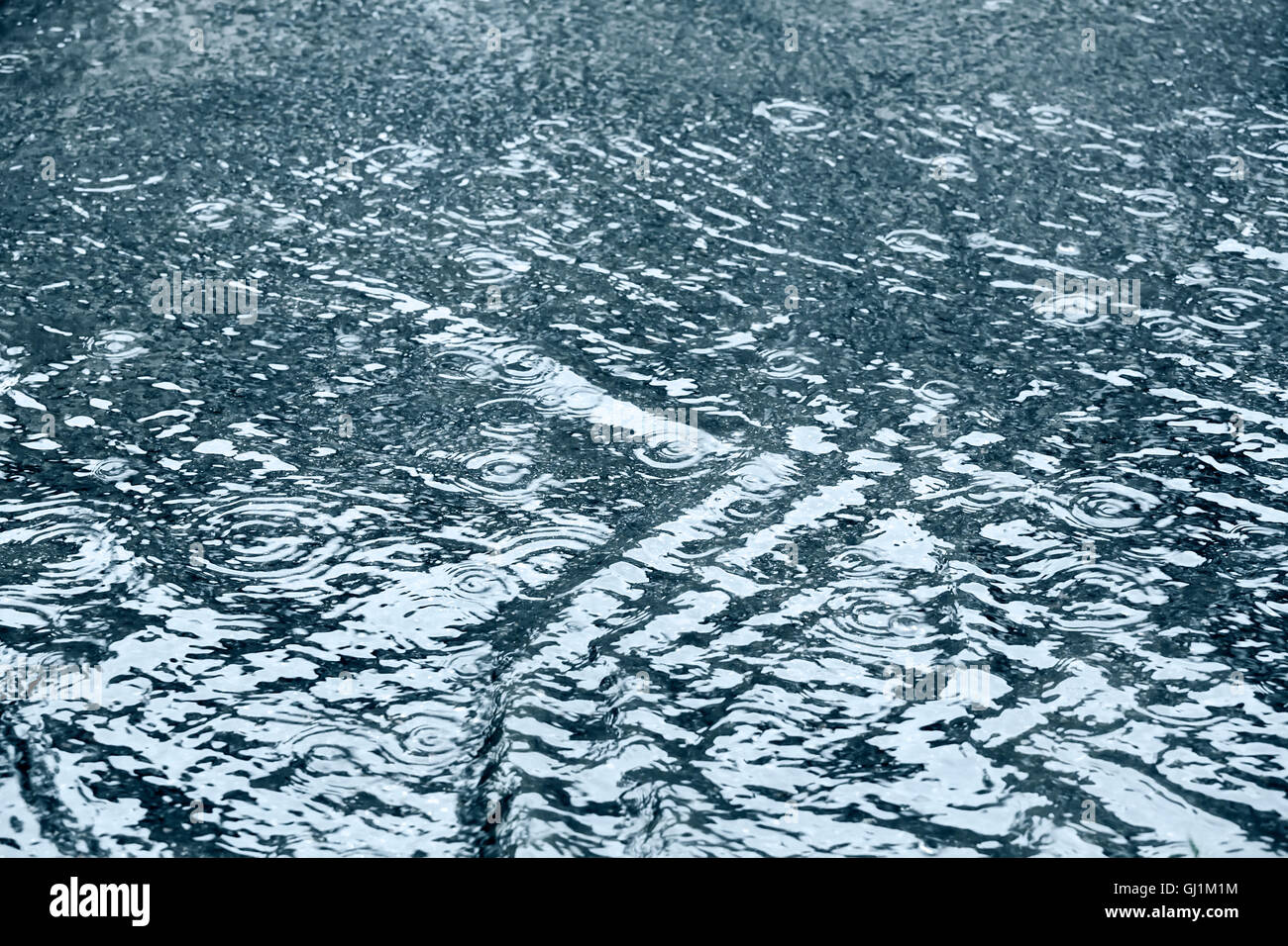 Raindrops and ripples in a puddle Stock Photo - Alamy