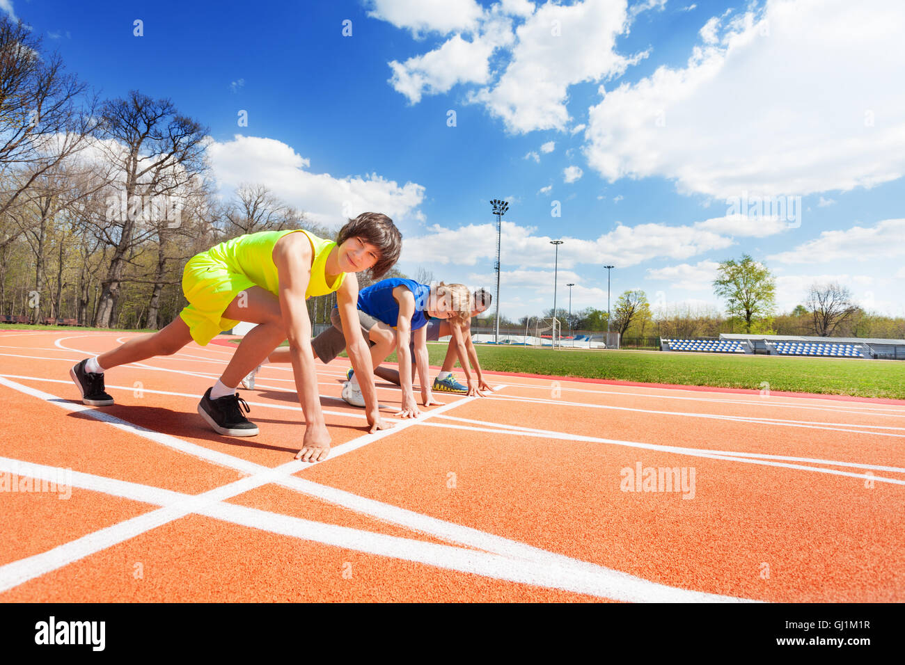 Three teenage athletes lined up ready to race Stock Photo - Alamy