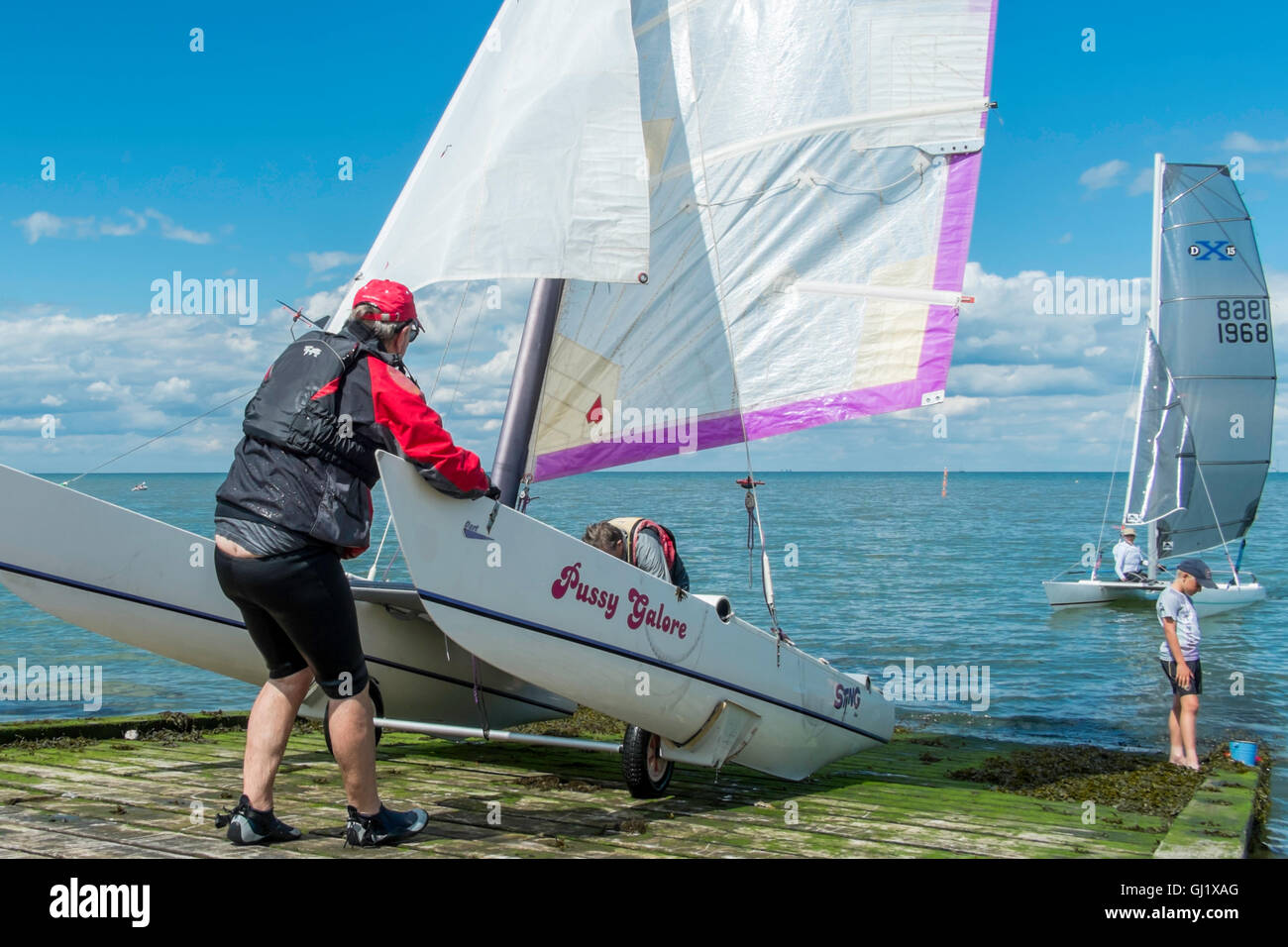 Sailors pulling and pushing their catamaran up the slipway, with ...