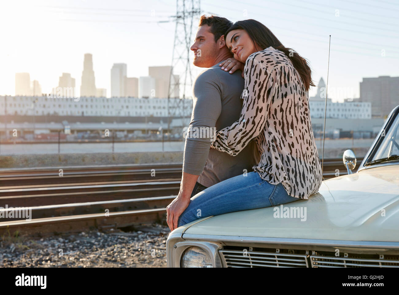 Couple hugging on car bonnet looking away, Los Angeles, California, USA ...