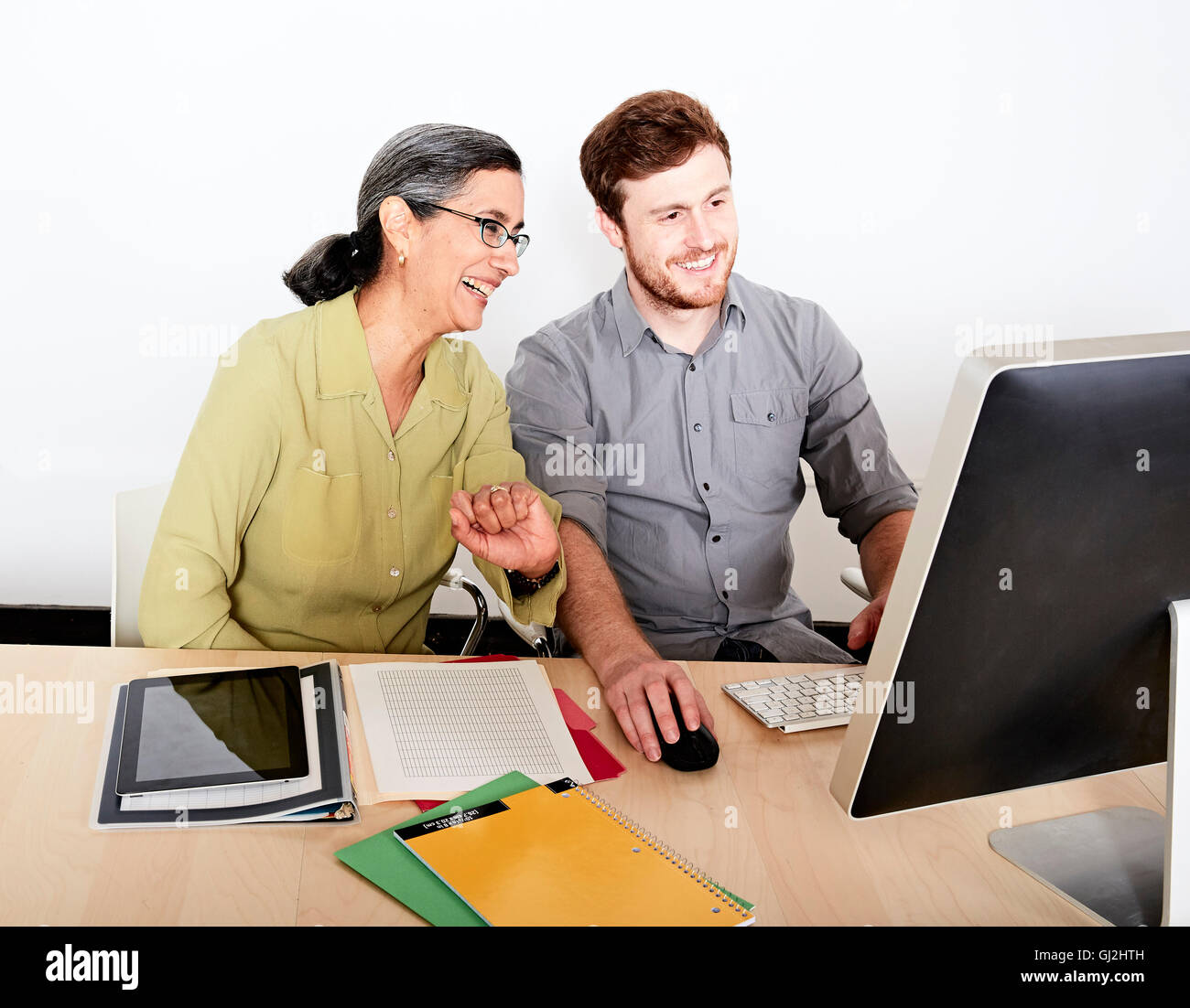 Colleagues looking at computer monitor smiling Stock Photo - Alamy