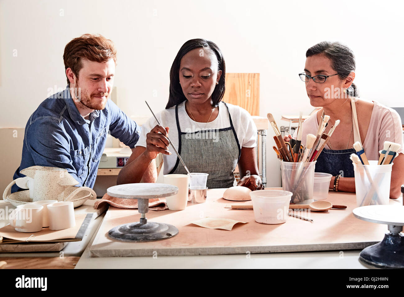 Group of people painting pottery in workshop Stock Photo - Alamy