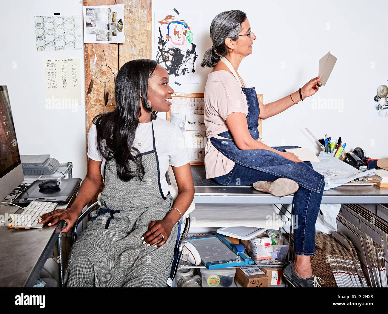 Woman at desk wearing aprons looking at colour swatch Stock Photo - Alamy