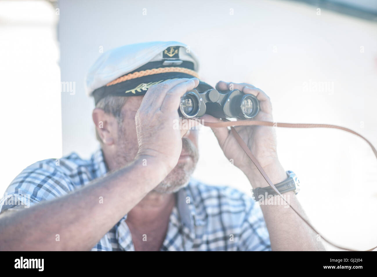 Boat captain looking through binoculars on boat, Cape Town, South ...