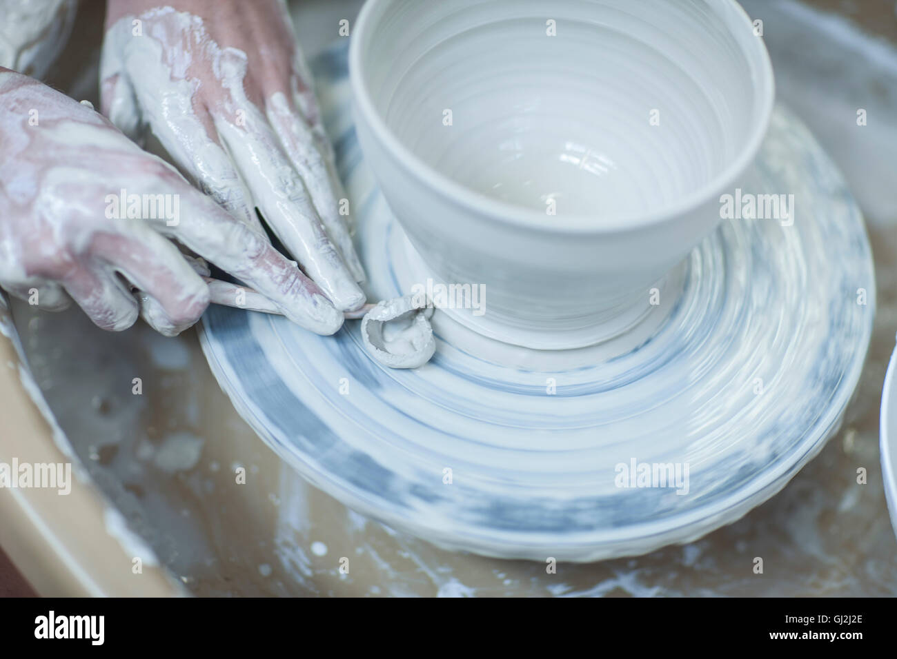 Close up of female potter's hands scraping clay bowl on pottery wheel ...