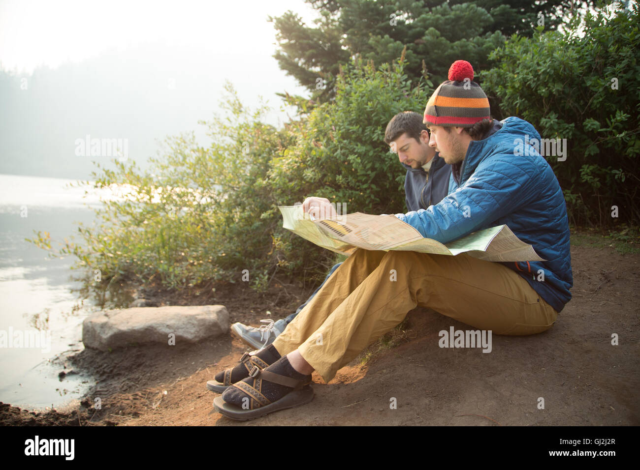 Two young male hikers reading map by lake, Mount Hood National Forest ...