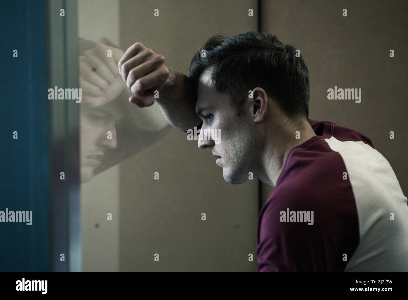 Man leaning against window looking out Stock Photo - Alamy