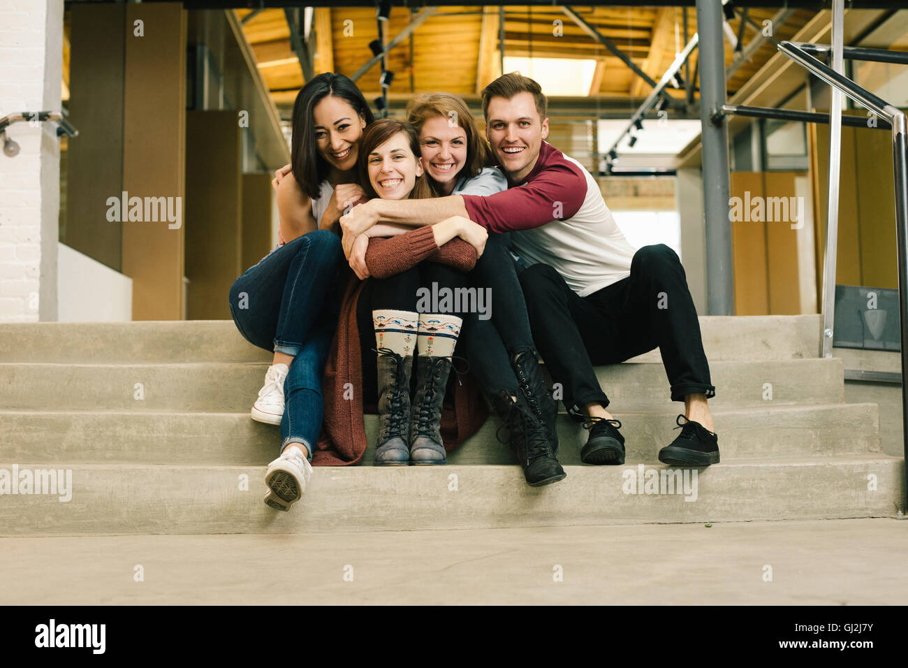 Friends sitting on steps hugging Stock Photo - Alamy