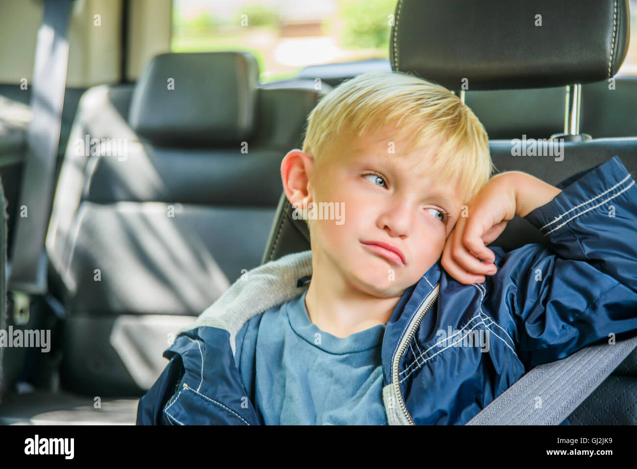 Young boy sitting in back of vehicle, bored expression Stock Photo - Alamy