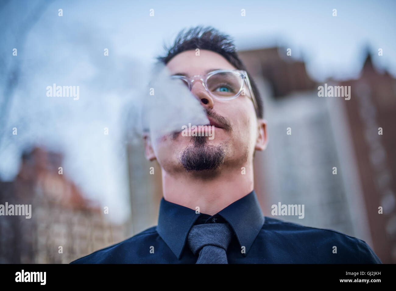 Young man outdoors, exhaling smoke Stock Photo - Alamy