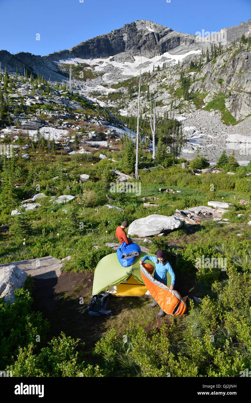 Backpacking couple packs up tent and sleeping bags at Fault Lake in the ...