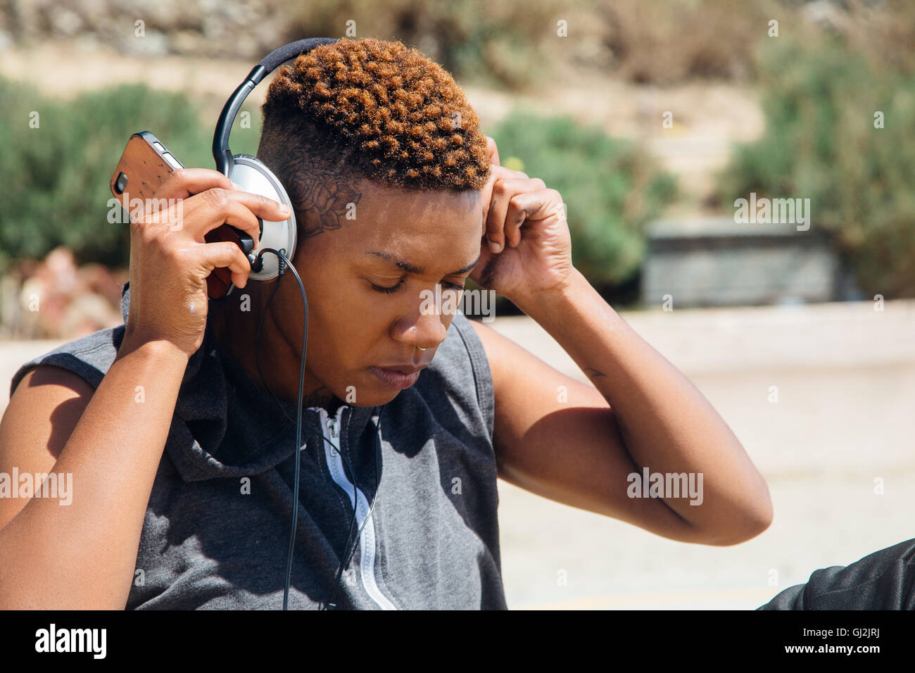 Woman wearing headphones holding smartphone looking down Stock Photo ...