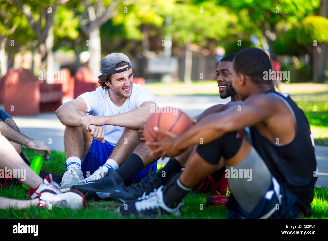 Group of male friends sitting together in park, laughing Stock Photo ...