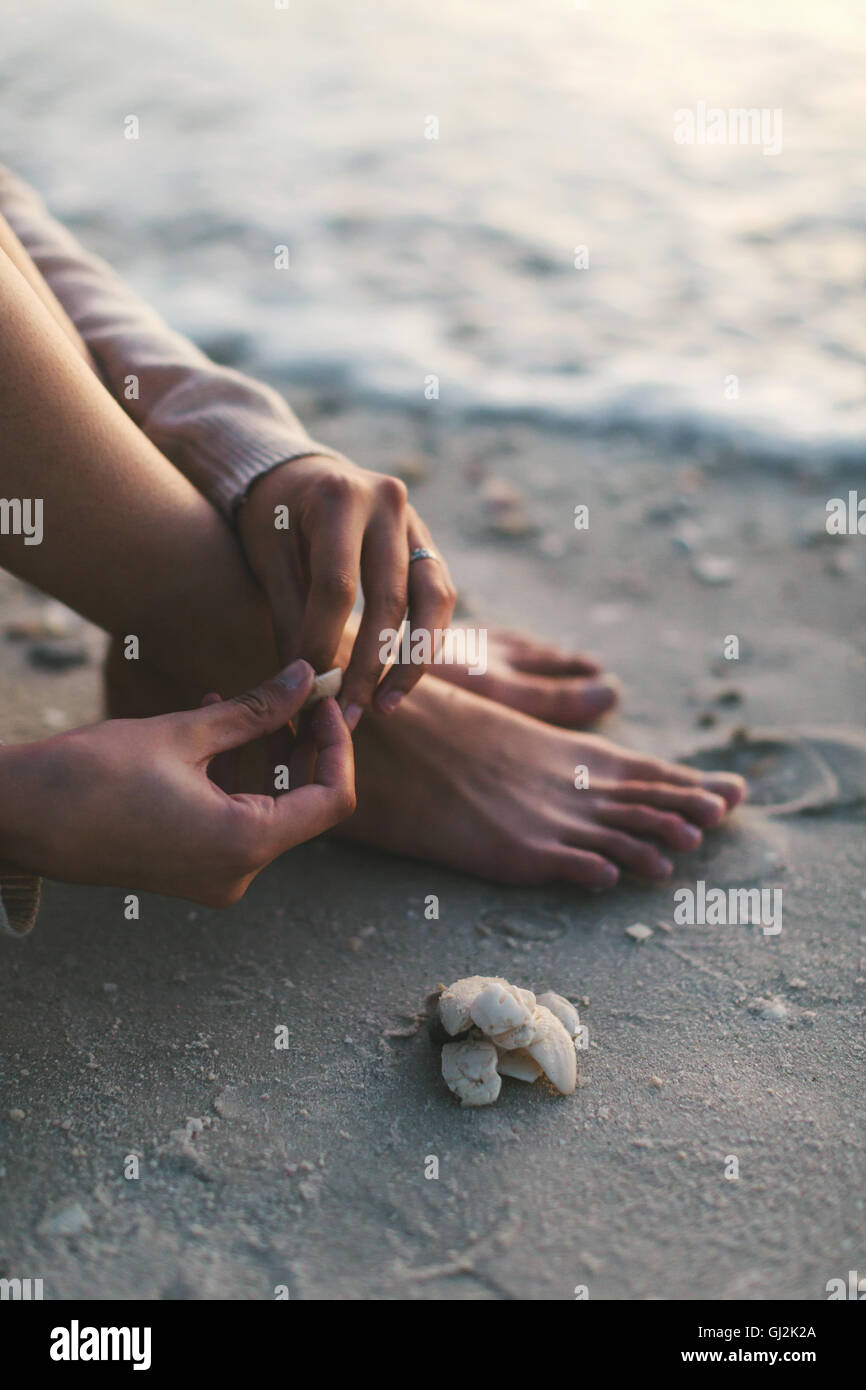 Woman playing with seashells on beach Stock Photo - Alamy