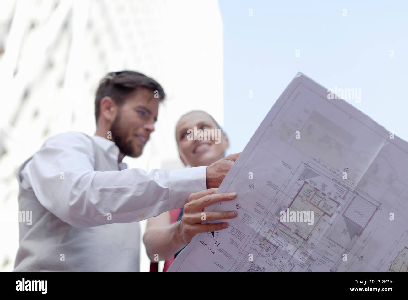 Mature man and woman outdoors, holding blueprints, low angle view Stock ...