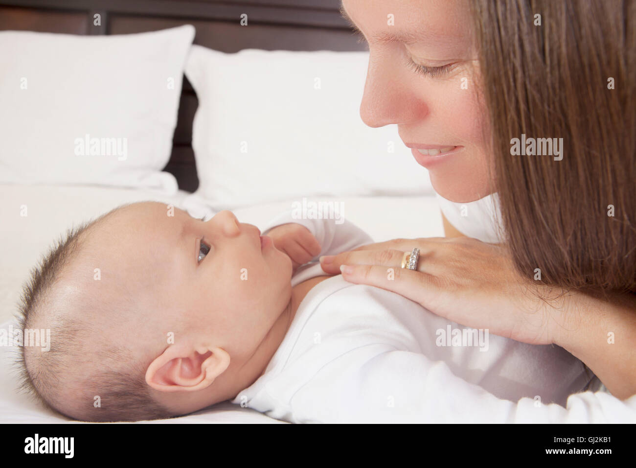 Mother admiring baby boy lying on bed Stock Photo - Alamy