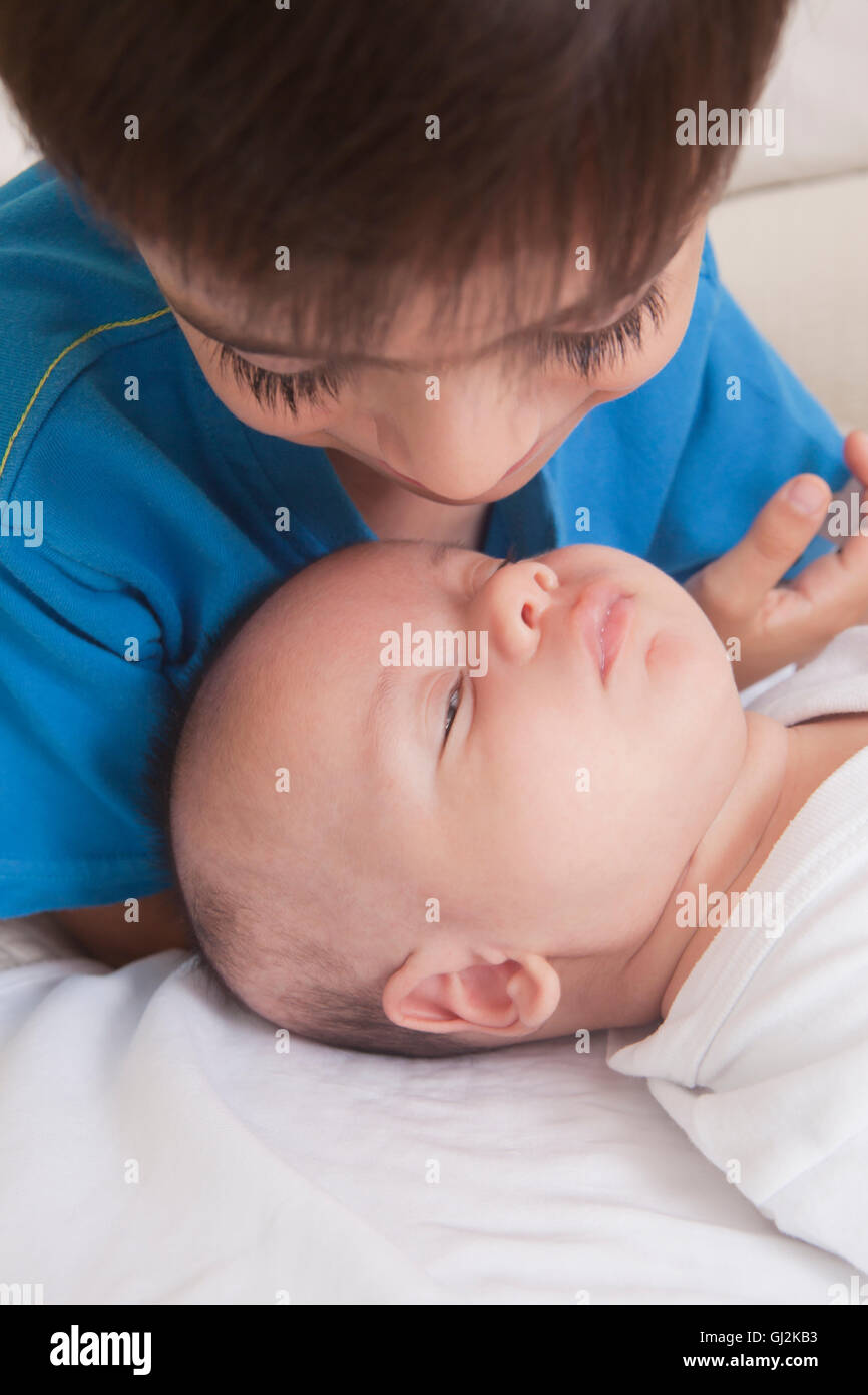 Boy looking down at baby boy Stock Photo - Alamy