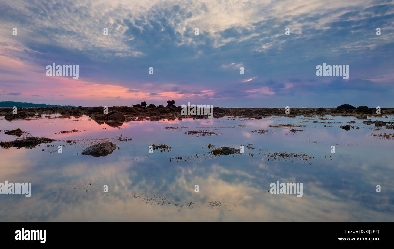 Colourful sunrise, stones and reflections in low tide ocean water Stock ...