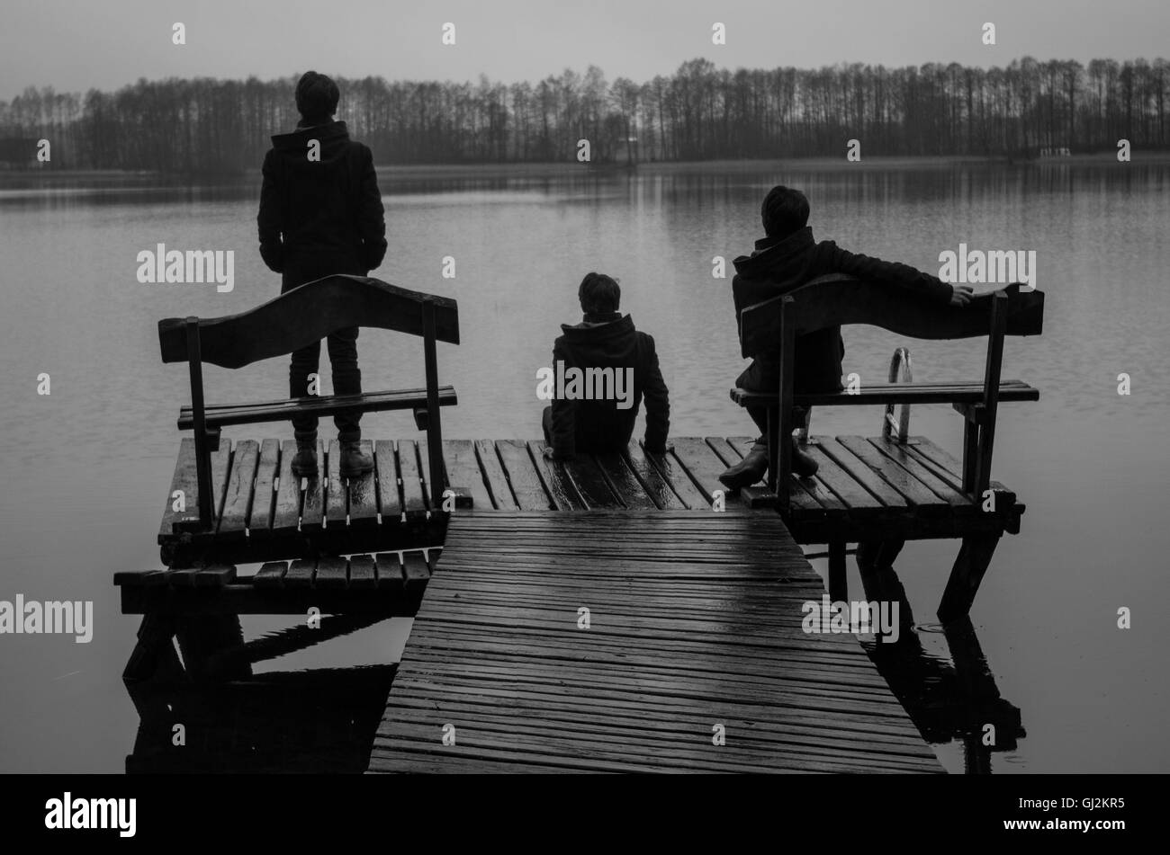 3 people sitting on a bridge that's in a lake Stock Photo - Alamy