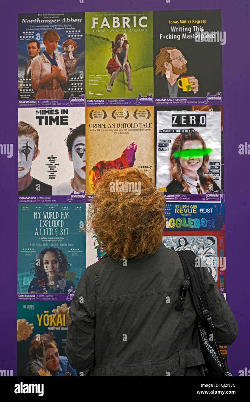 A red haired woman reading the posters for shows at the Underbelly ...