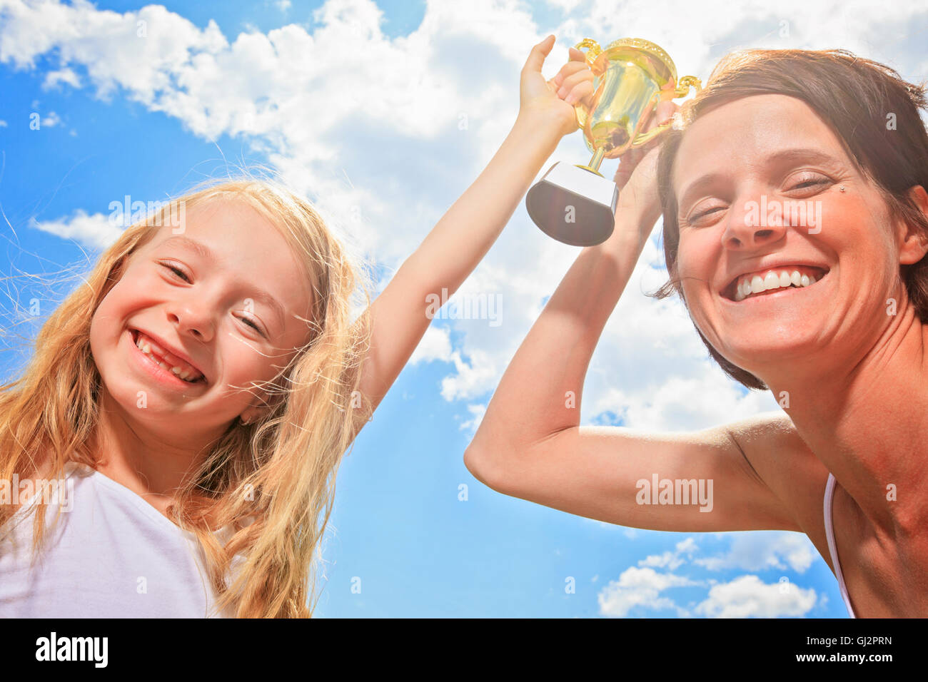 A Happy mother and daughter holding a trophy high up Stock Photo - Alamy