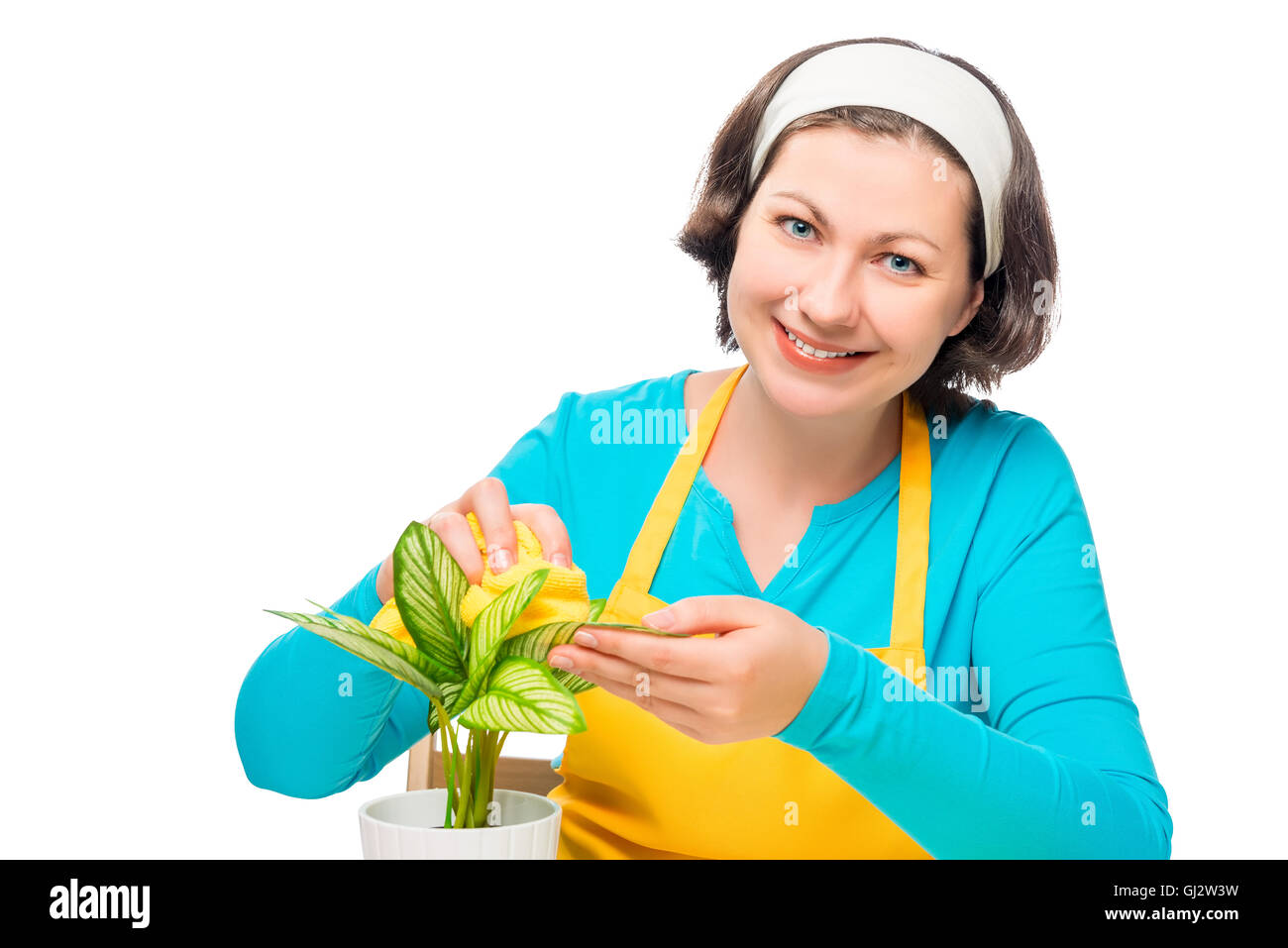 woman sitting at the table and rubs the flower leaves on white ...